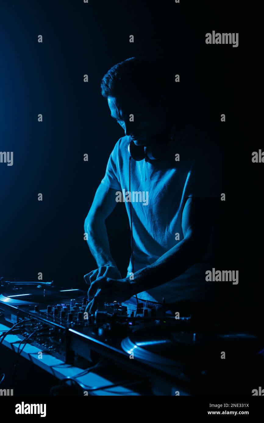 Silhouette of club DJ playing music on techno party. Disc jockey mixing ...