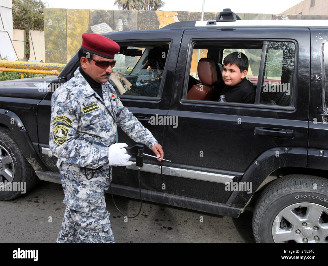 An Iraqi police officer uses a scanner device to inspect a car at a ...