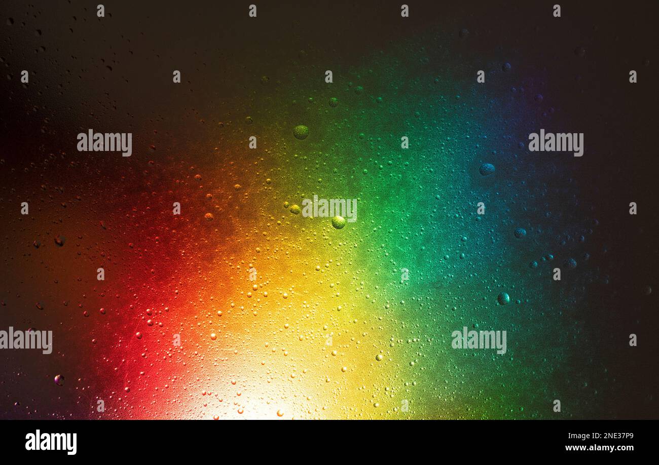 Dark glowing background with water drops with an explosion of rainbow ...