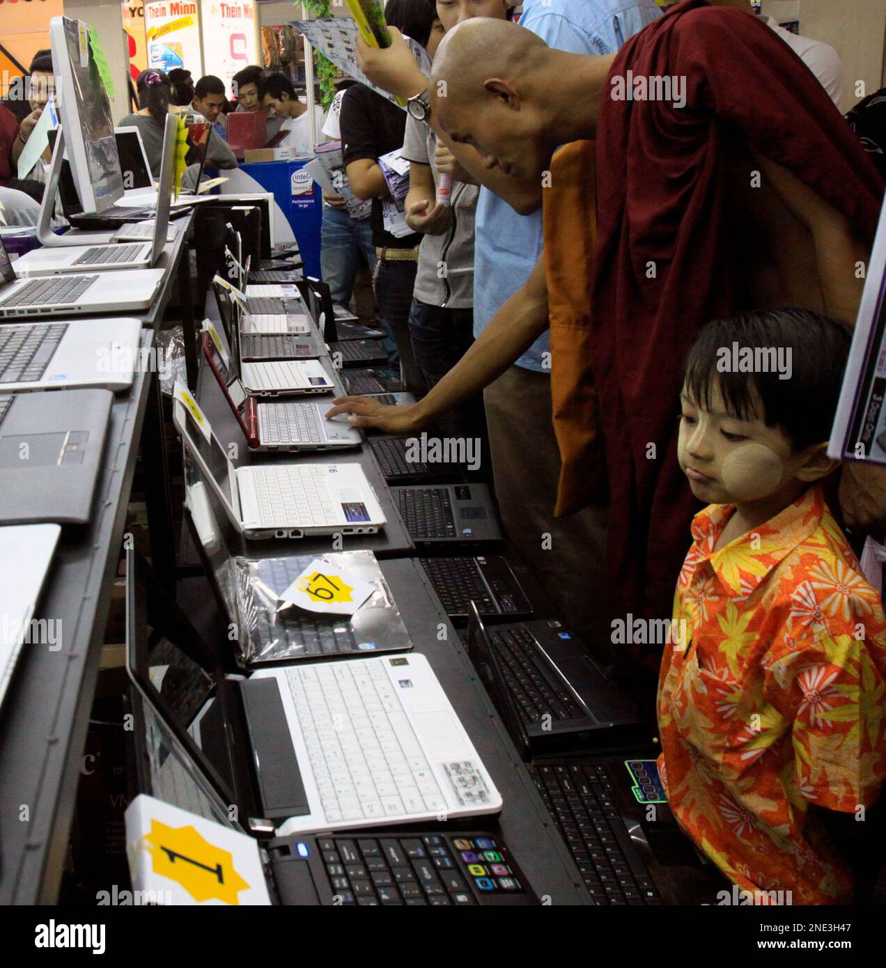 A Buddhist monk and visitors observe laptop computers on display during ...