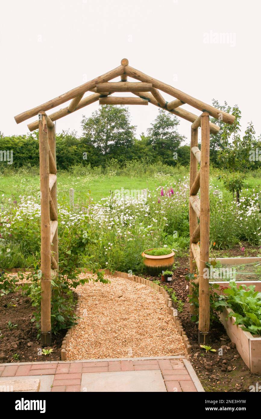 A close up of a newly built handmade wooden garden arch and young ...