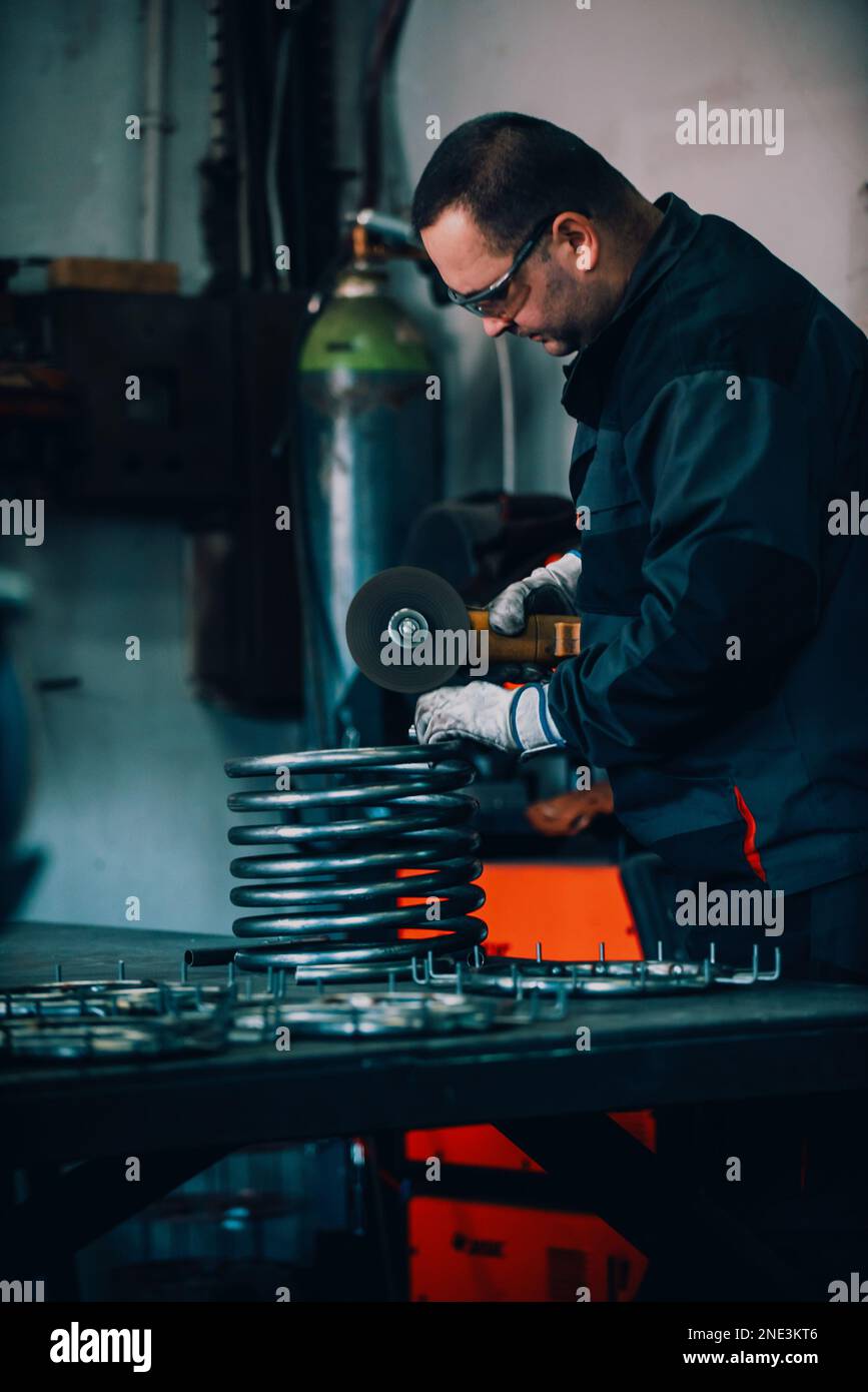 Locksmith in special clothes and goggles works in production. Metal ...