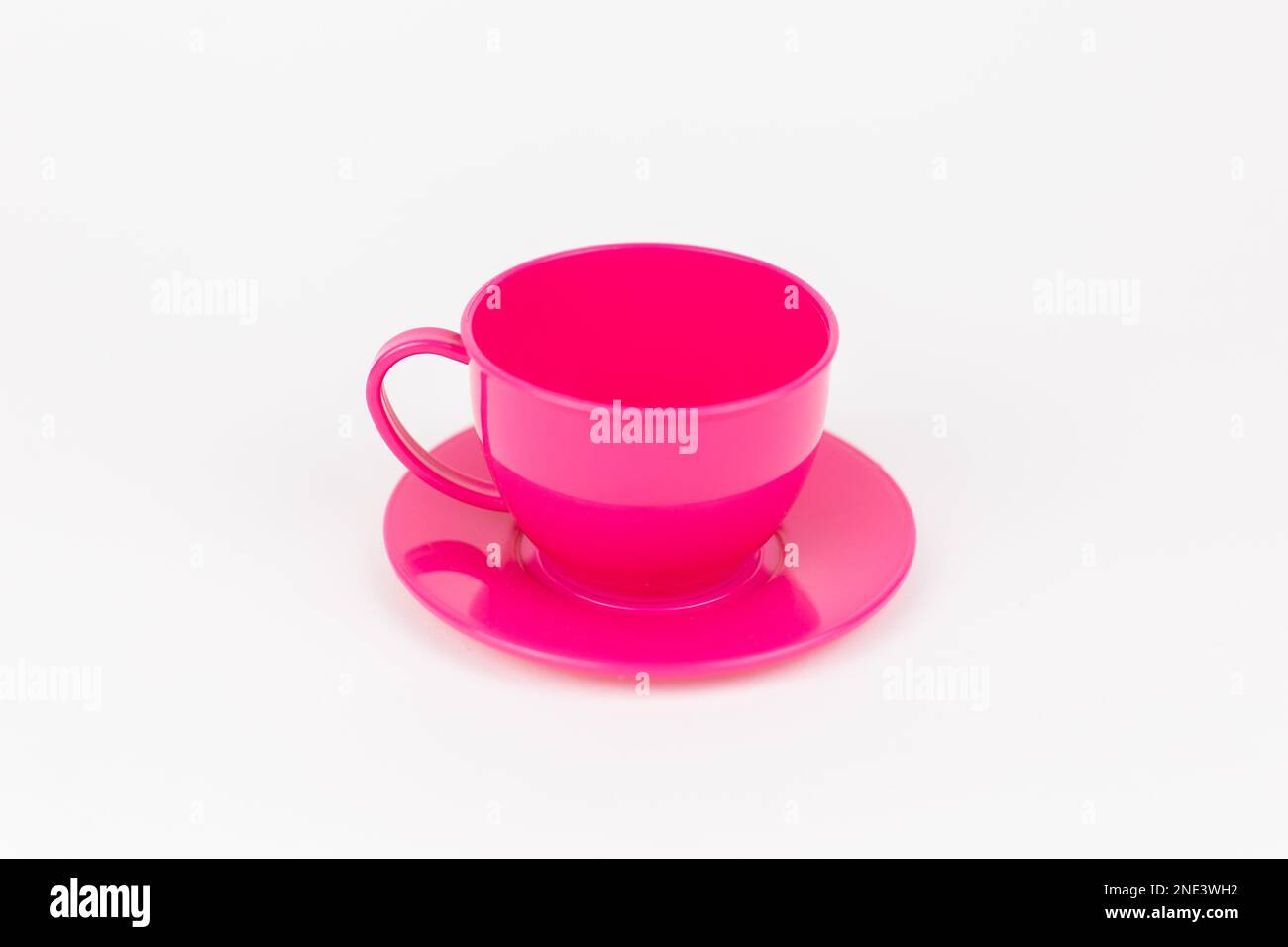 a pink plastic cup with saucer on white background Stock Photo - Alamy