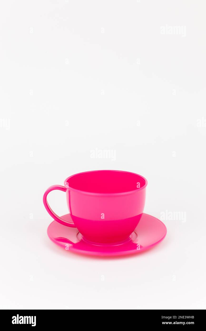 a pink plastic cup with saucer on white background Stock Photo - Alamy