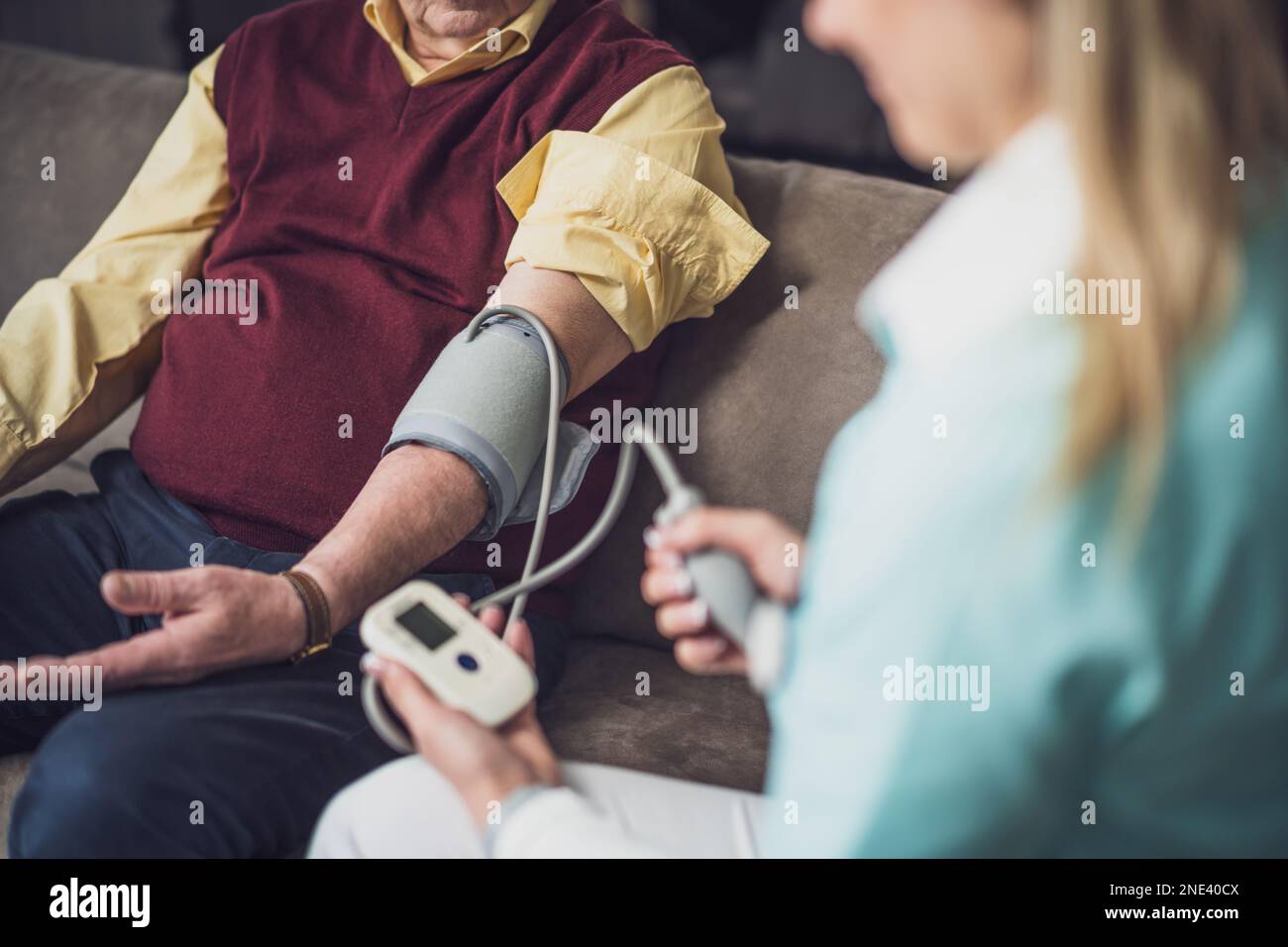 Home doctor is measuring blood pressure of old man at his home ...