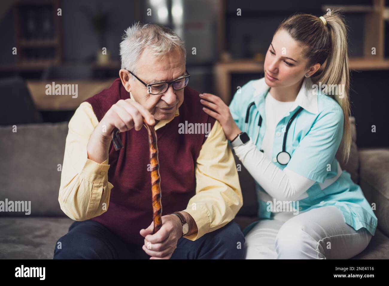 Nurse home caregiver is assisting old man at his home. Professional ...