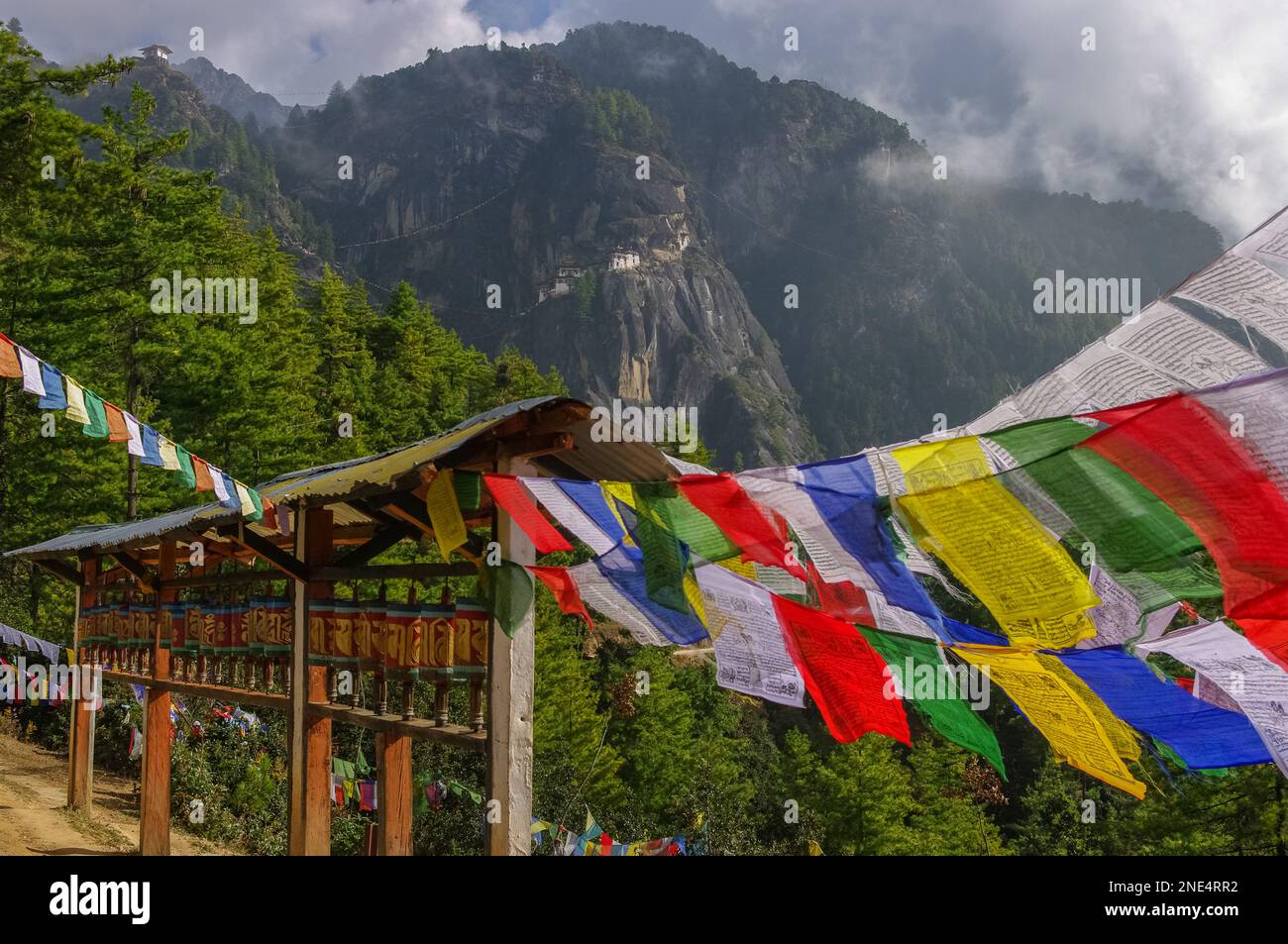 Traditional prayer mills and prayer flags on the path to cliff hanging ...