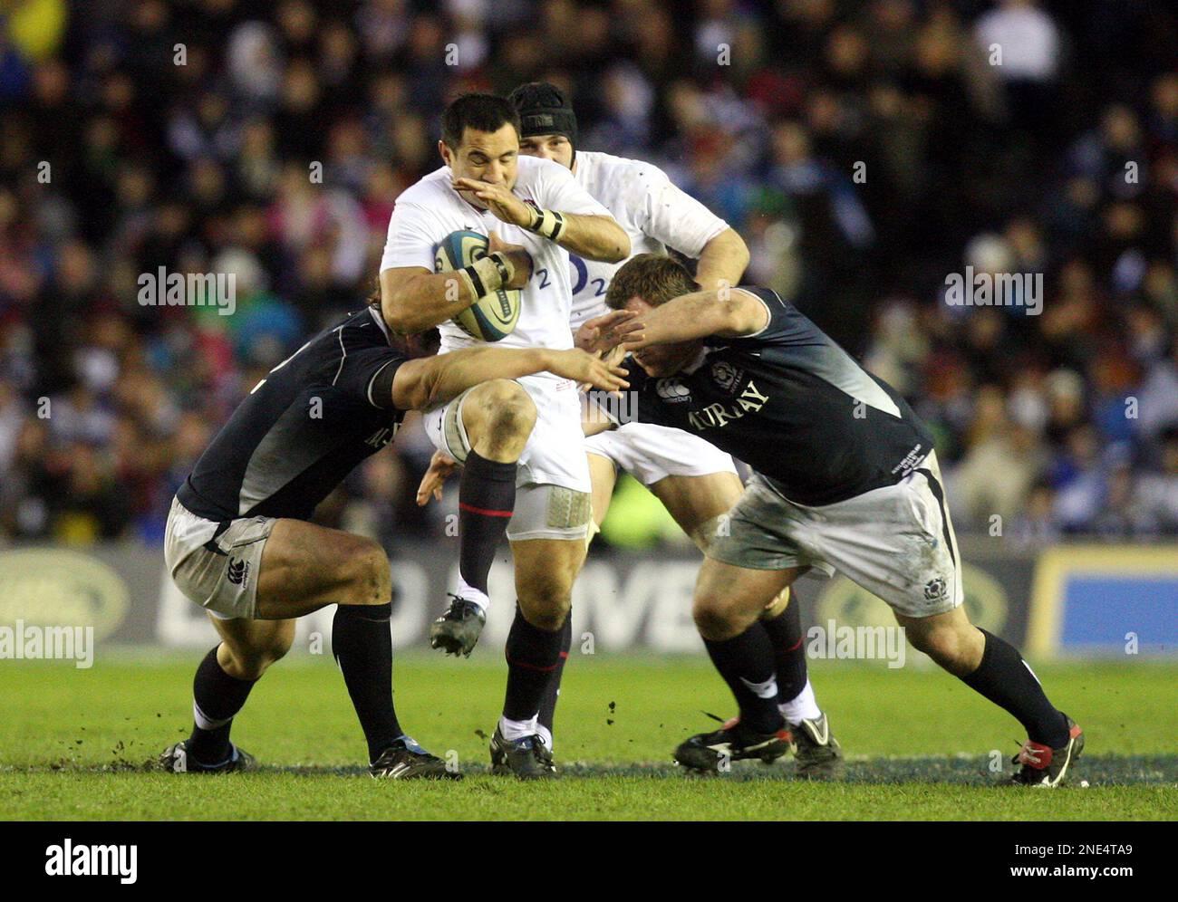 England's Riki Flutey, center, is tackled by Scotland's Ross Ford, left ...