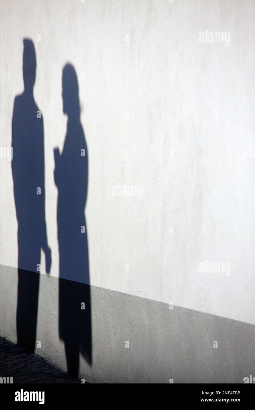 Shadow of two people on the wall, one holding a glass and the other ...