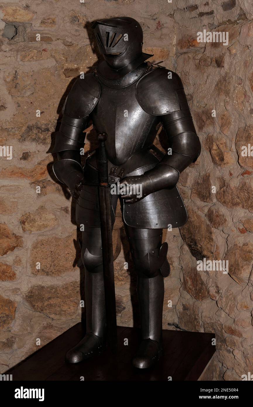 A full suit or panoply of engraved plate armour standing, holding a ...