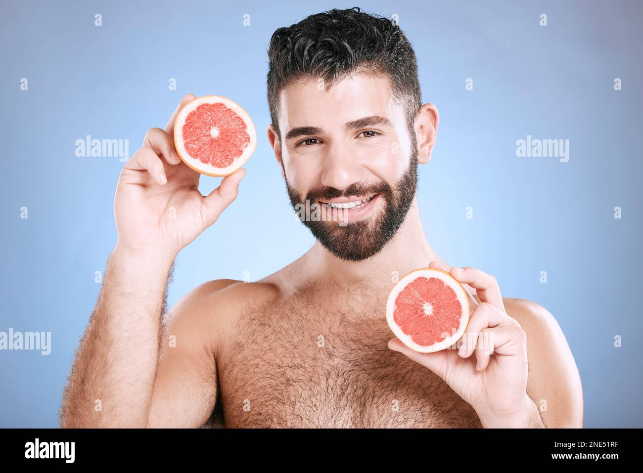 Portrait, skincare and grapefruit with a man model in studio on a blue background for natural ...