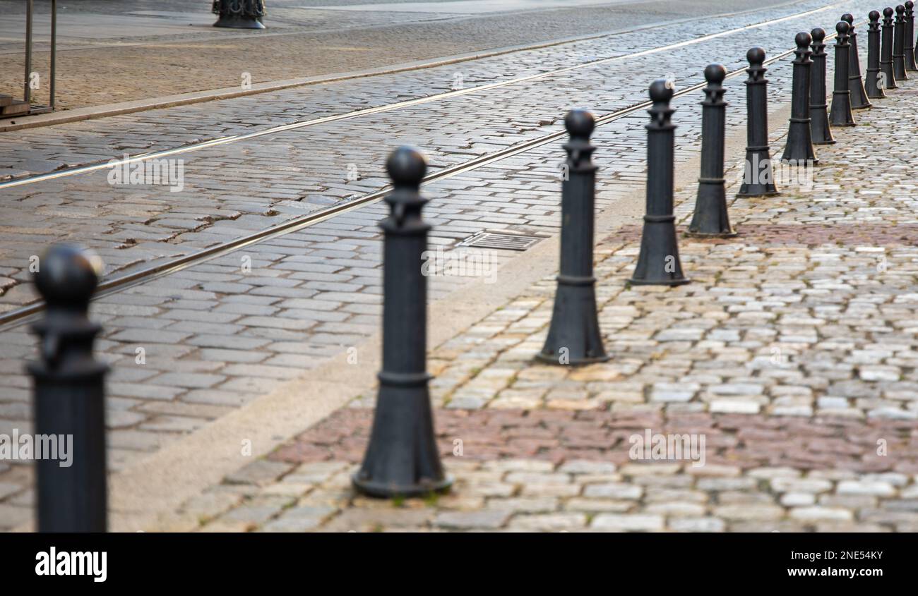 Black posts separating paved street and path Stock Photo - Alamy