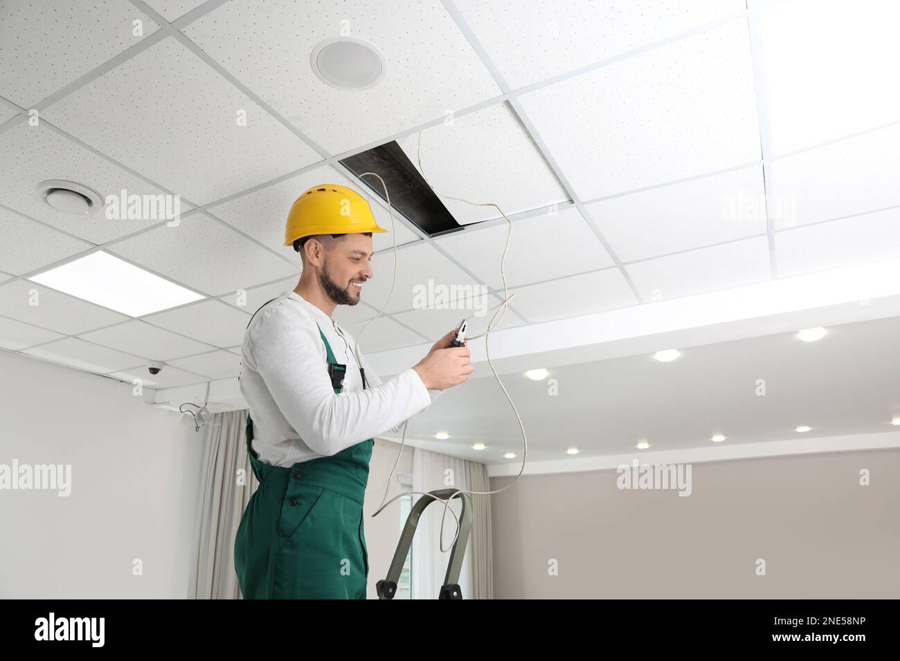 Electrician with pliers repairing ceiling wiring indoors Stock Photo ...