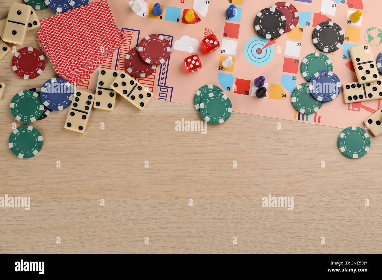 Elements of different board games on wooden table, flat lay. Space for ...
