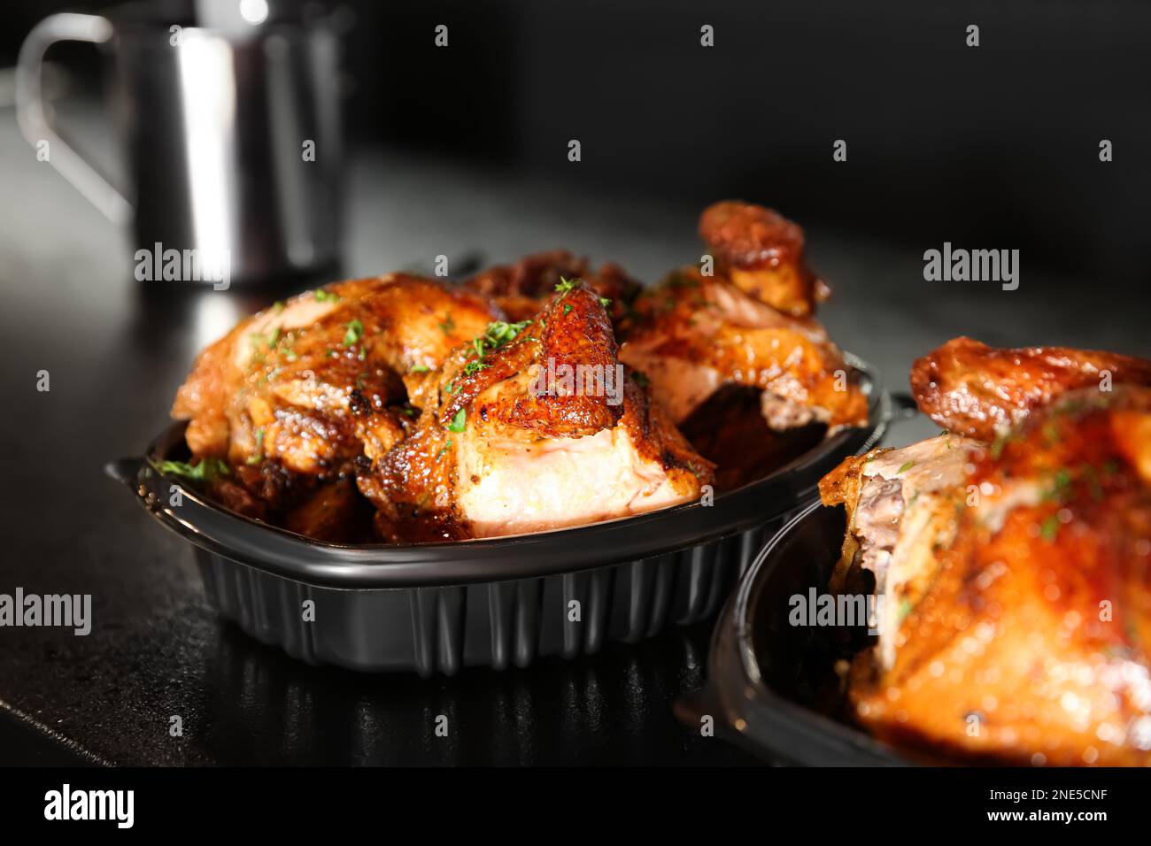Cooked pieces of grilled chicken in plastic containers on bar counter ...