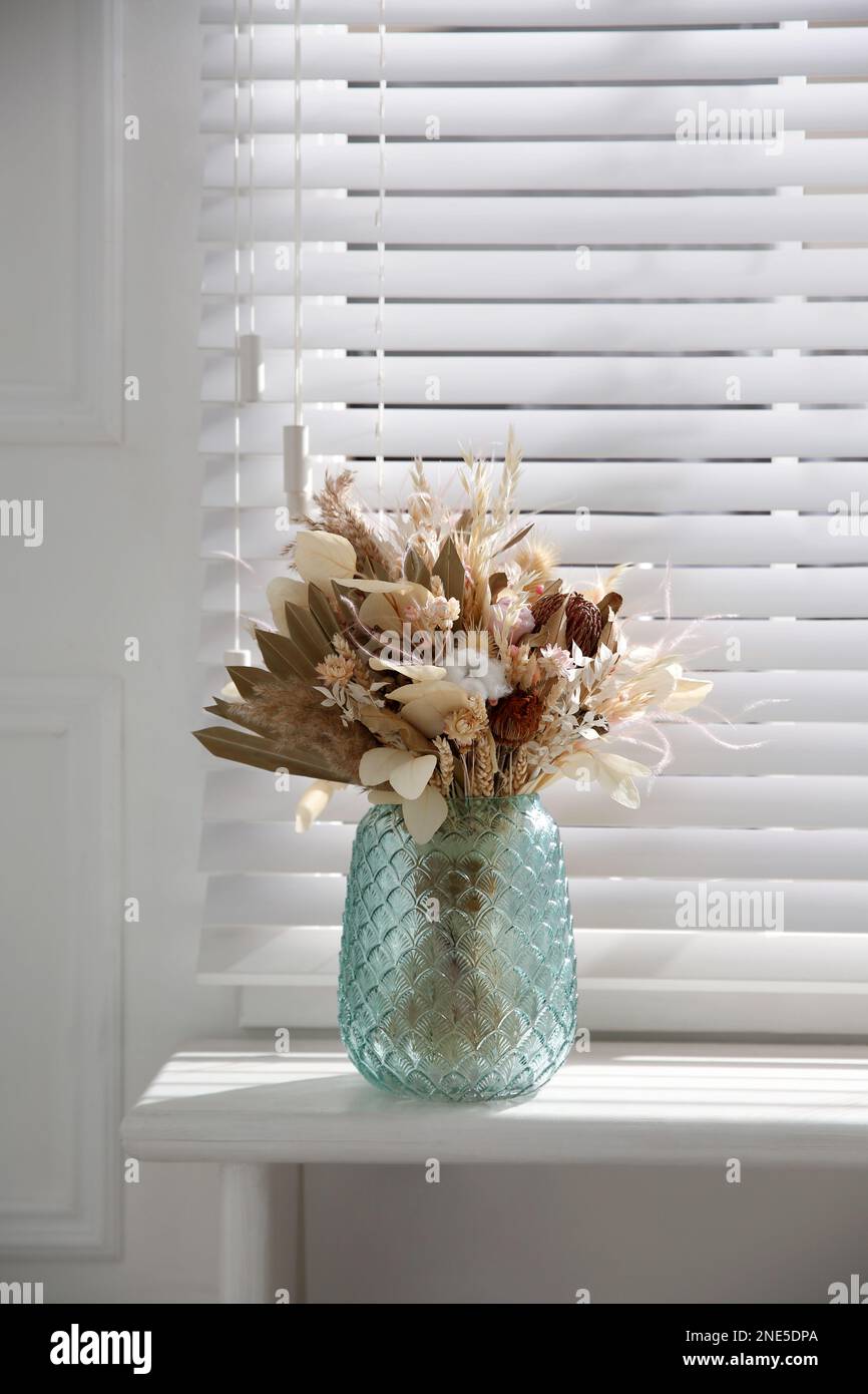 Beautiful dried flower bouquet in glass vase on white windowsill Stock ...
