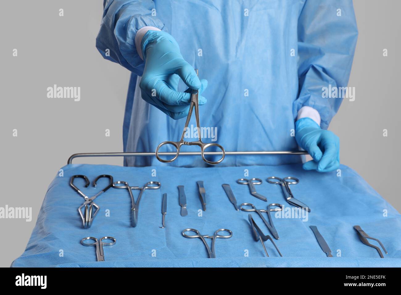 Doctor giving scissors near table with different surgical instruments ...