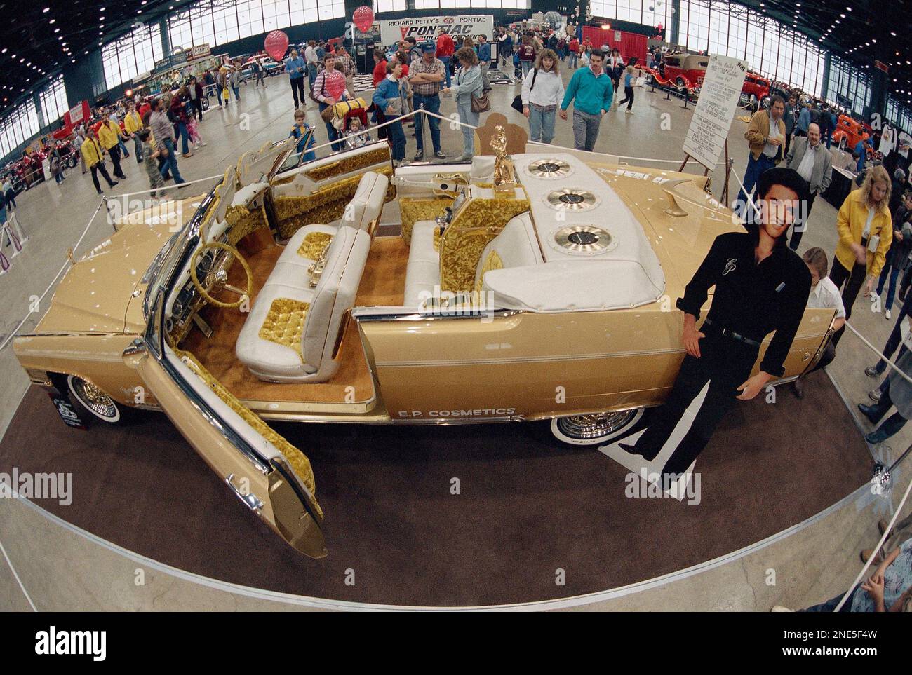 Crowds at an auto show look at a custom-made 1965 gold Cadillac ...