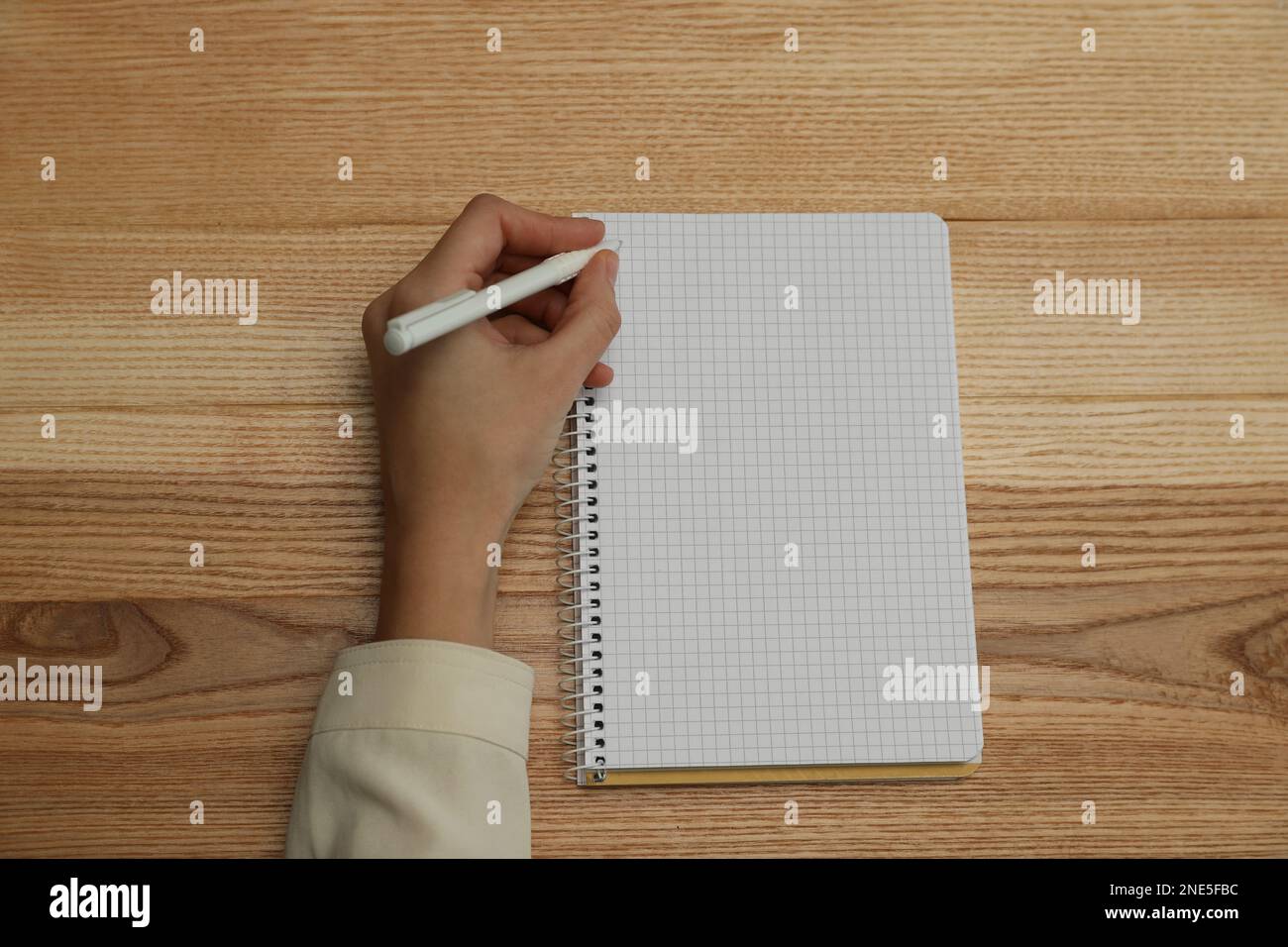Left-handed woman writing in notebook at wooden table, top view Stock ...