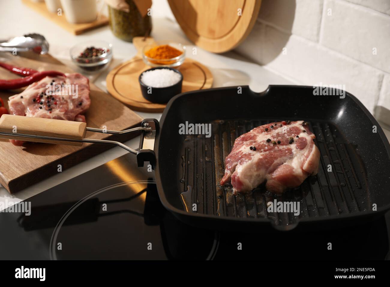 Frying pan with fresh raw meat on stove Stock Photo - Alamy
