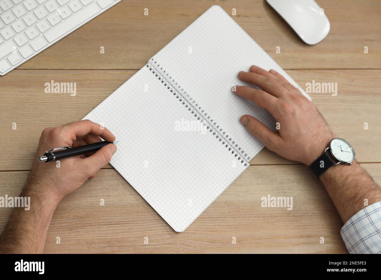 Left-handed man writing in notebook at wooden table, top view Stock ...