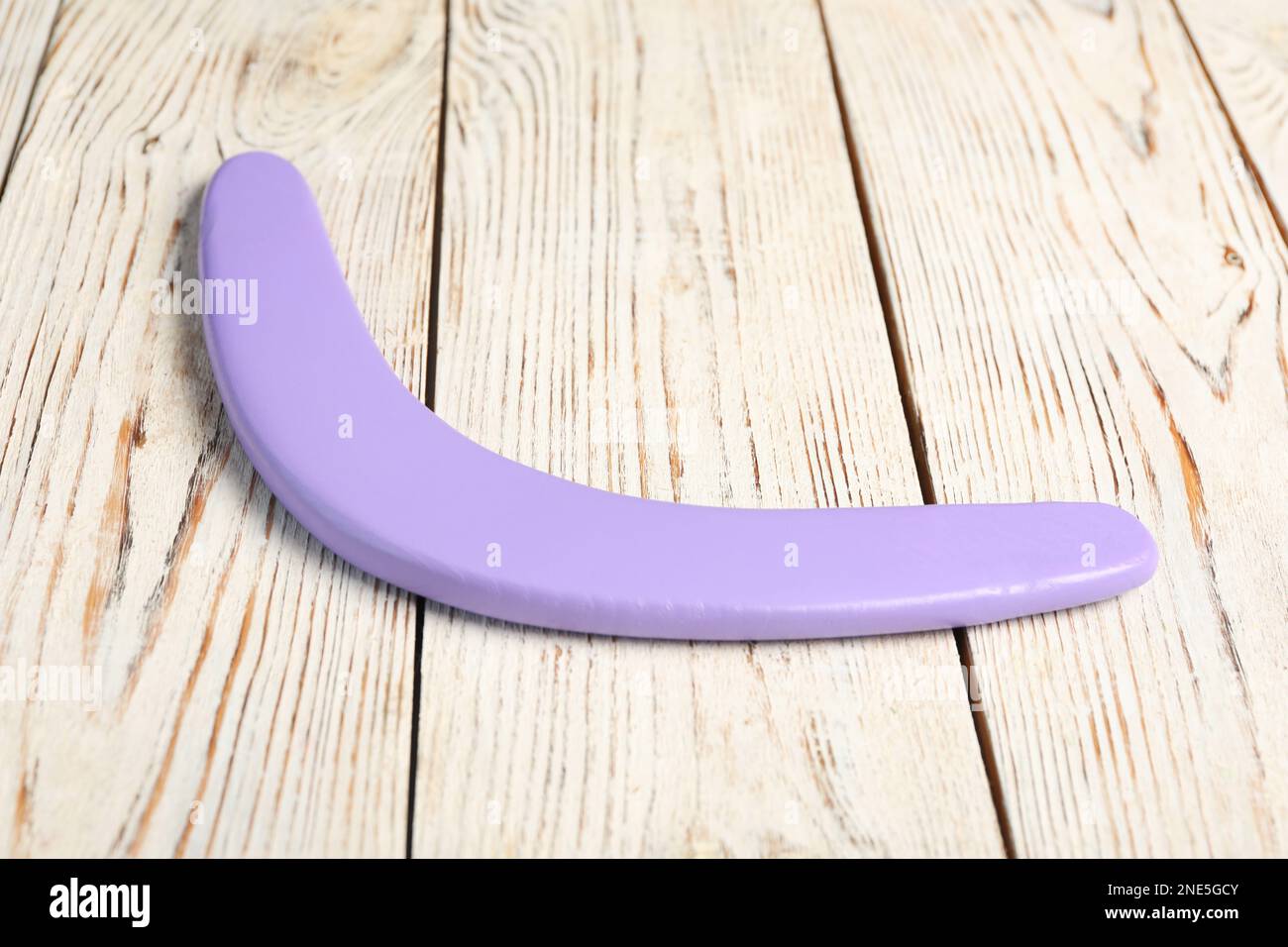Purple boomerang on white wooden background. Outdoors activity Stock ...