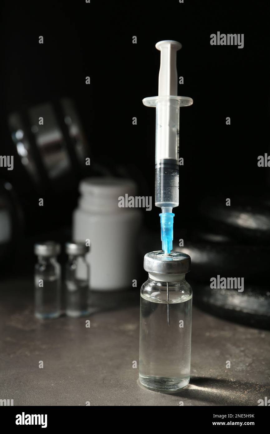 Vial and syringe with drug near sports equipment on grey table, space ...
