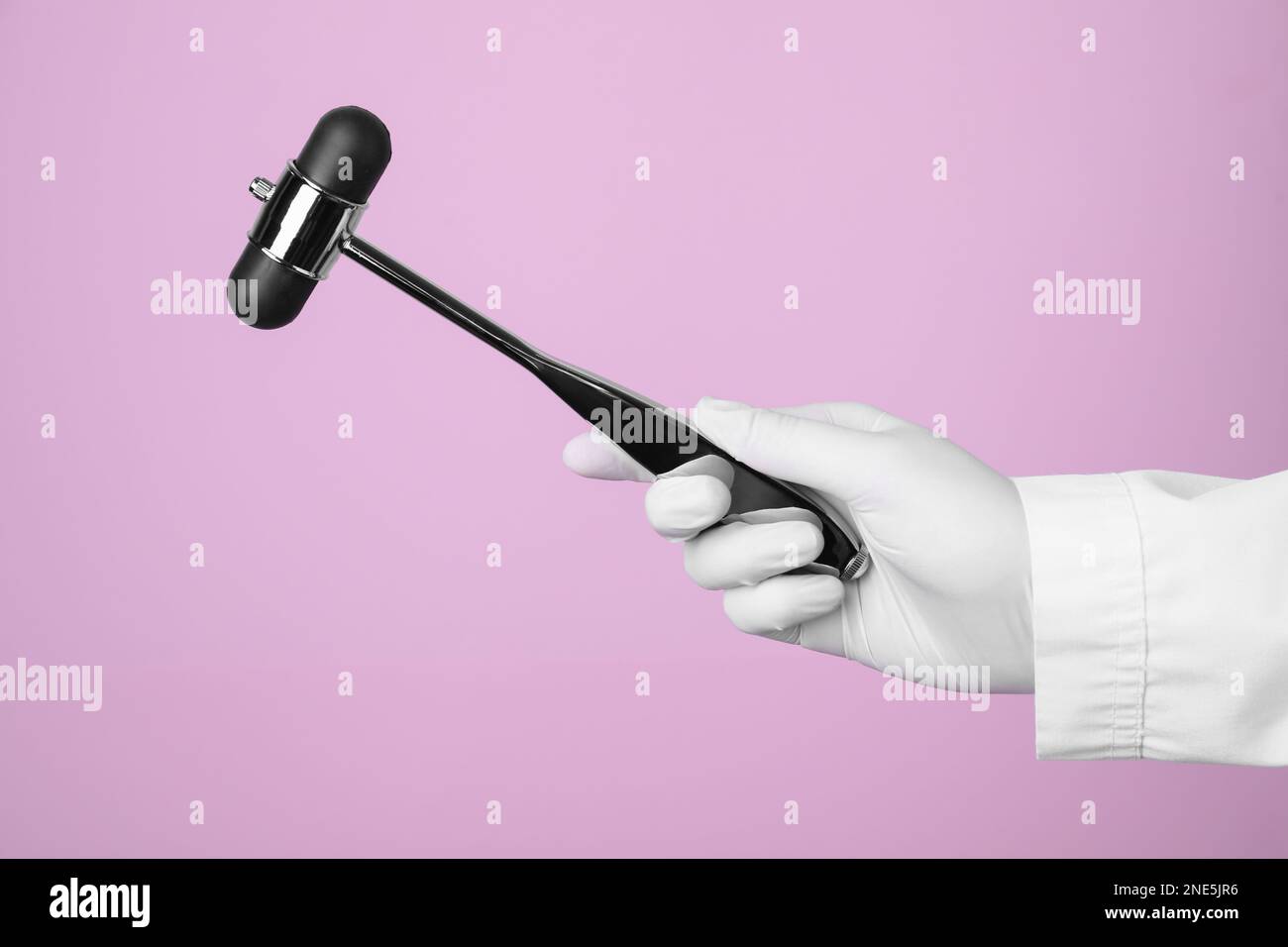 Doctor holding reflex hammer on pink background, closeup. Nervous ...