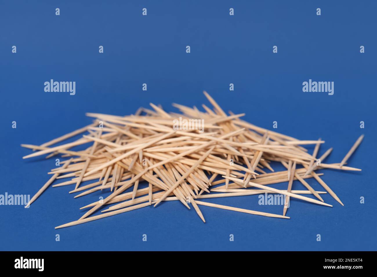 Pile of wooden toothpicks on blue background Stock Photo - Alamy