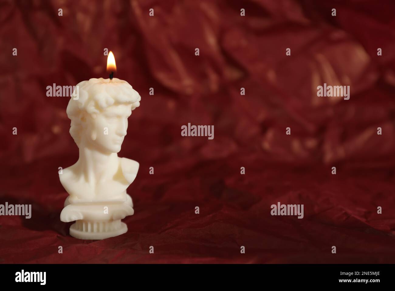 Beautiful burning David bust candle on red crumpled parchment. Space ...
