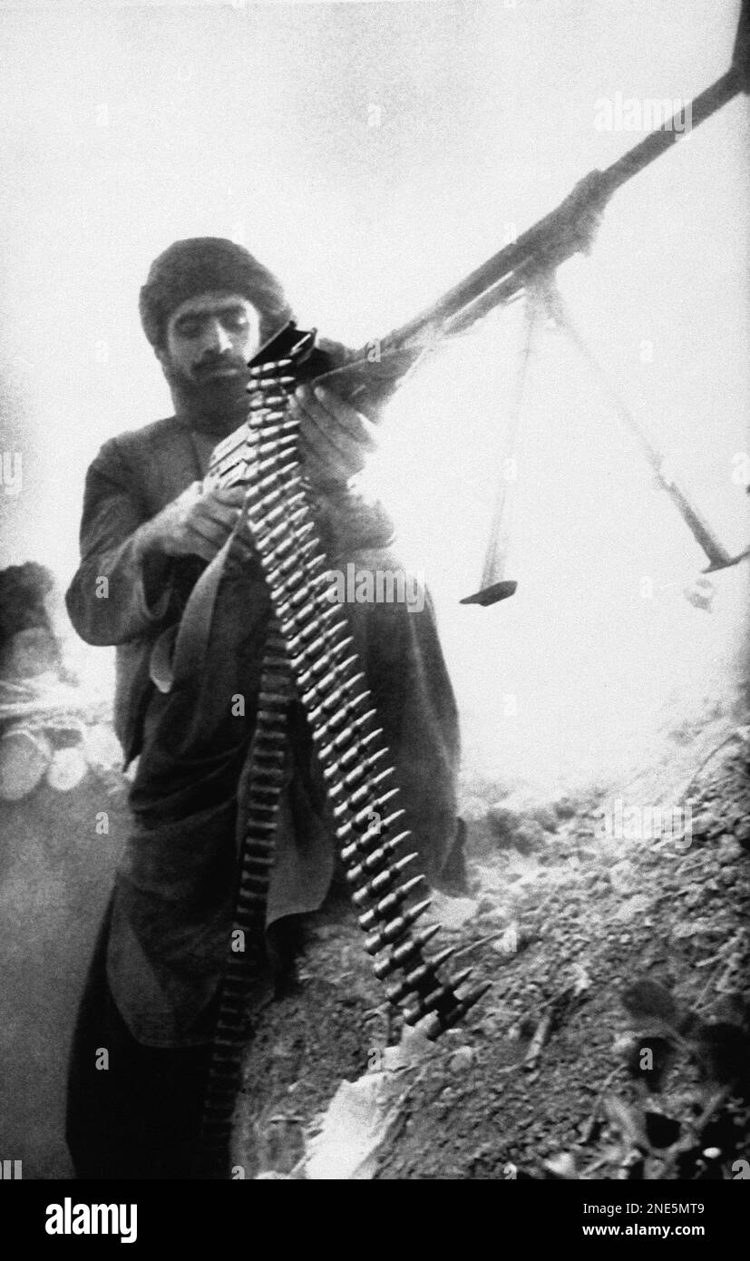 Armed with a PK machine gun, an Afghan guerrilla exchanges fire with ...