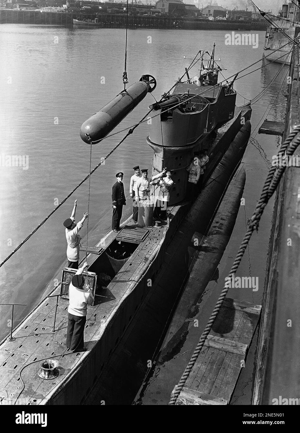 Royal Navy submariners hoist a torpedo on to a submarine at a British ...