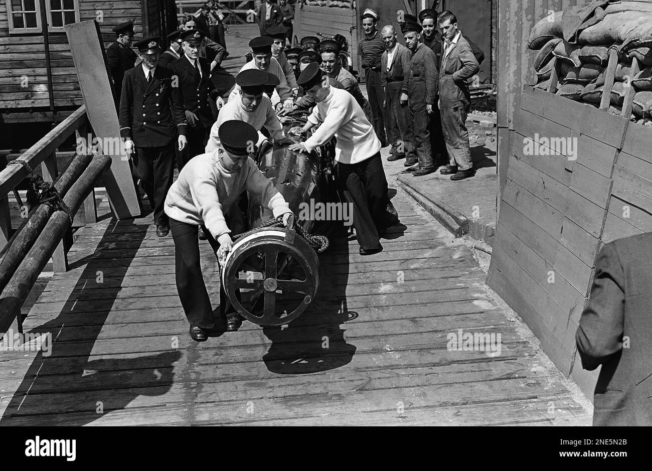 Royal Navy submariners roll a torpedo along, prior to its being loaded ...