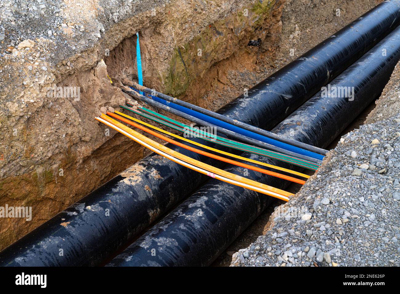 Trench with two laid heating pipes. Multicolored electrical cables ...