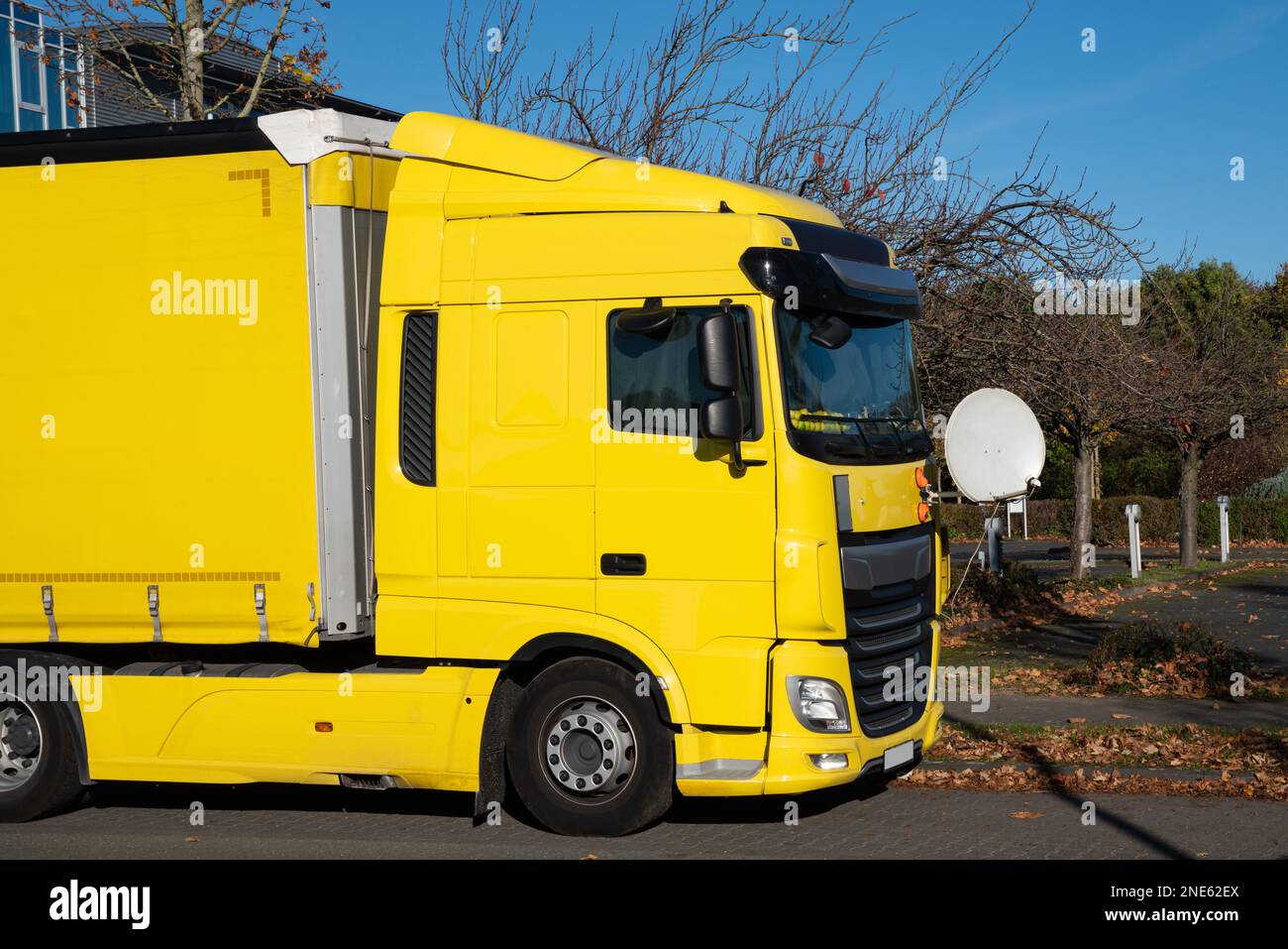 A large yellow truck parked with a satellite dish attached to the cab ...