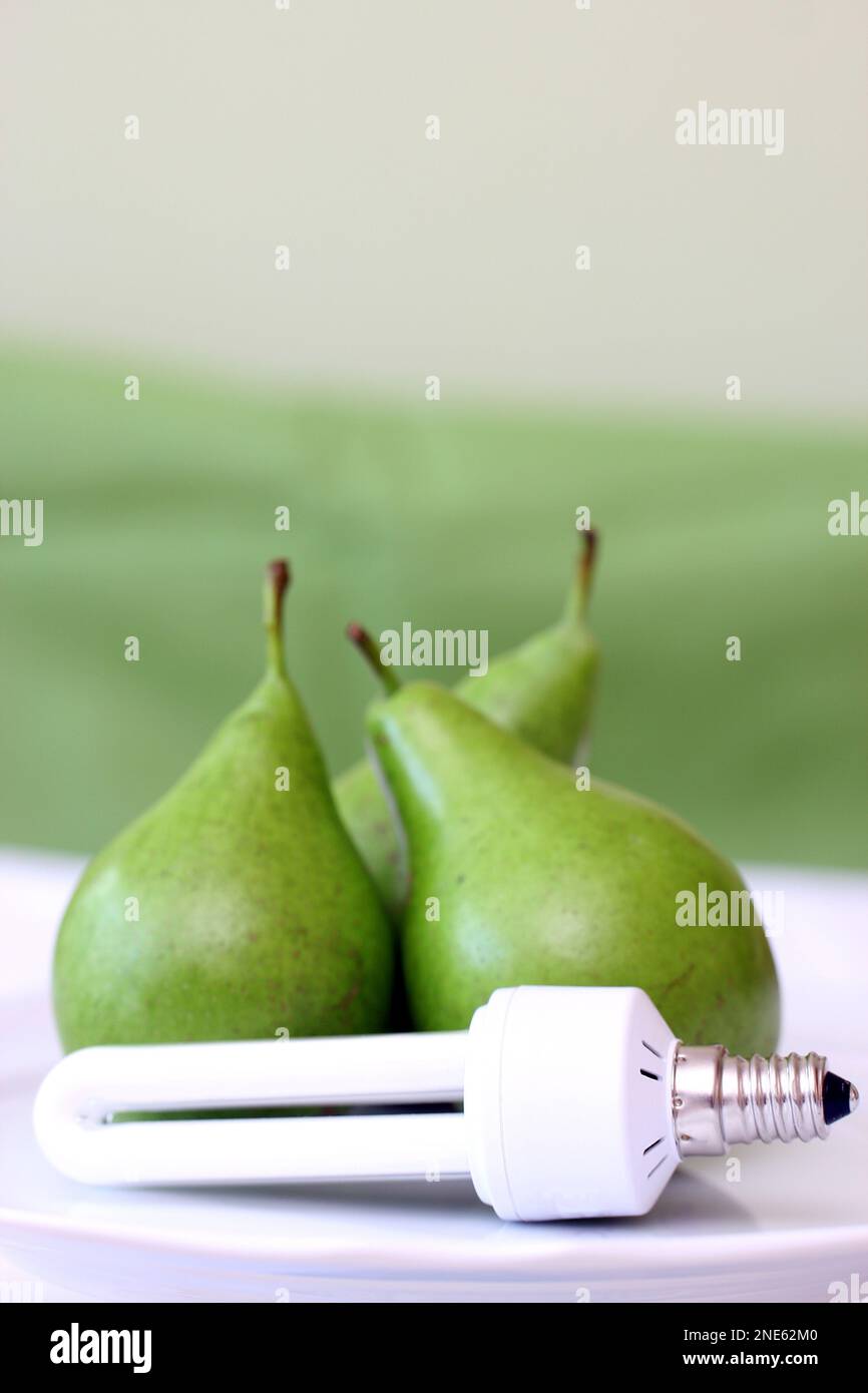 green pears on a plate with energy saving lamp Stock Photo - Alamy