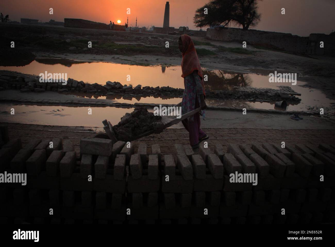 A Pakistani woman carries mud as the raw material to make bricks at a ...