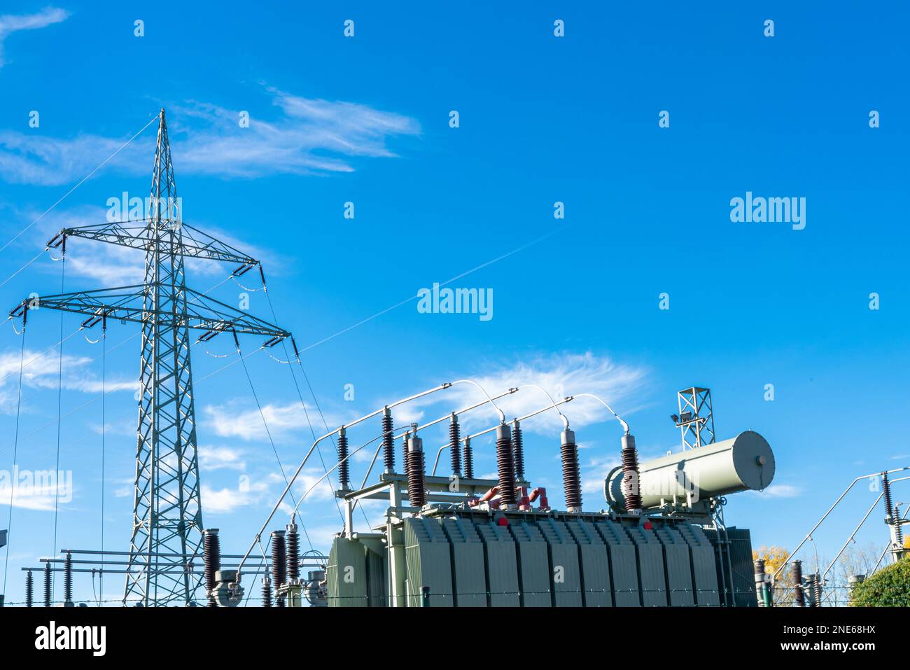 An electrical transformer and a high-voltage mast against a blue sky ...