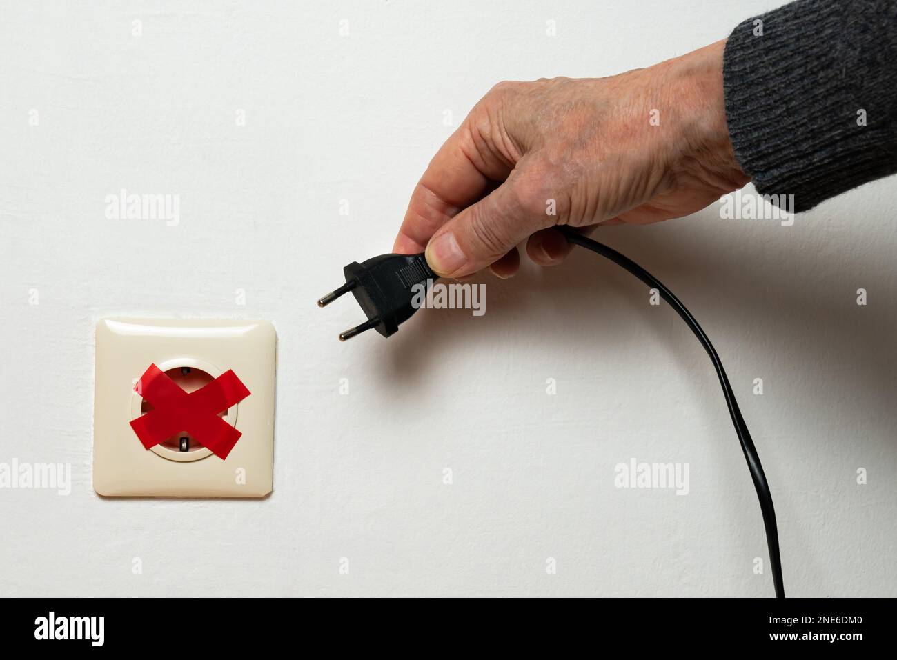 A man's hand is trying to plug a plug into an electrical outlet that is ...