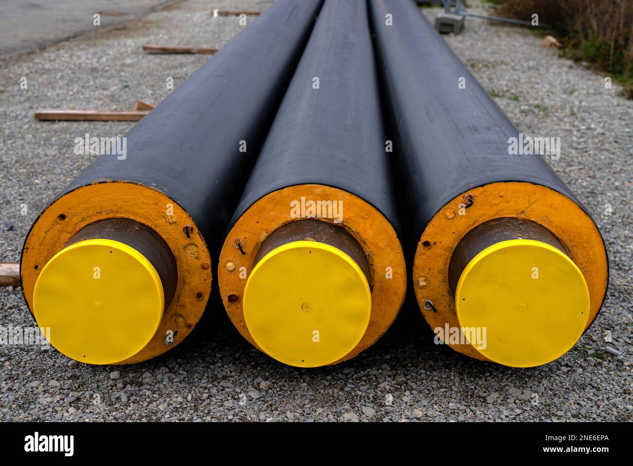 Three isolated heating pipes with yellow plastic plugs lie on a ...