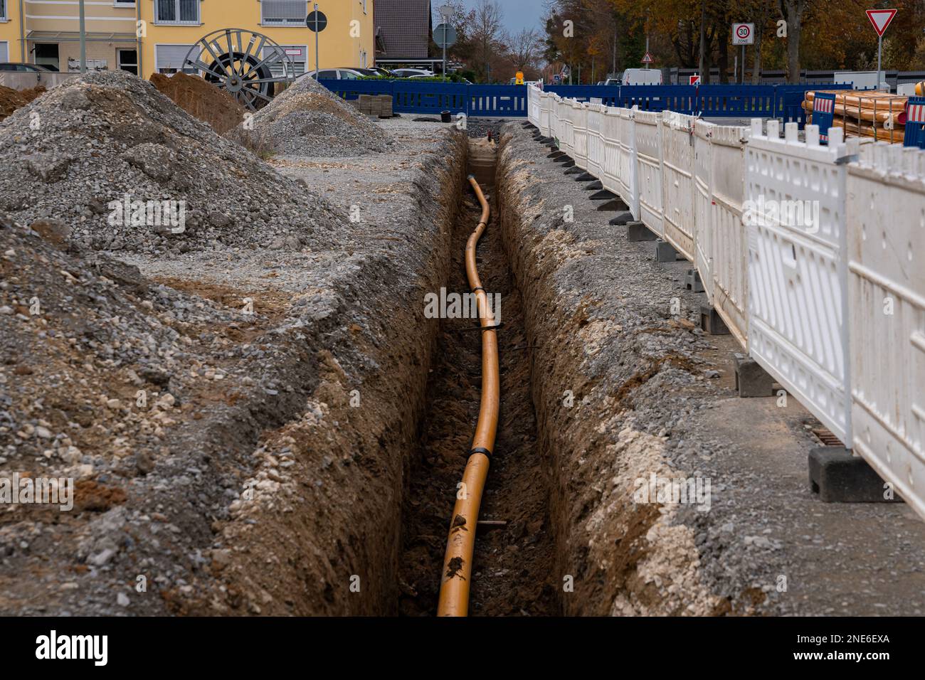 Trench with orange plastic pipe laid in it at construction site ...