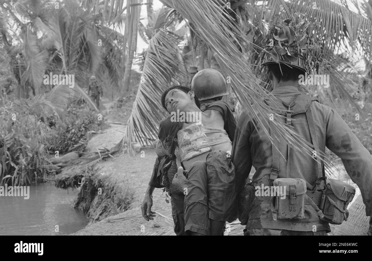 South Vietnamese troopers carry a wounded comrade to an aid following a ...