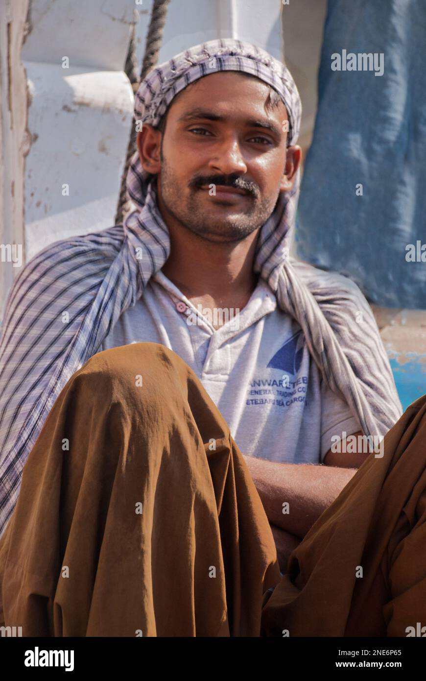 Asian worker taking a break whilst seated on a traditional cargo dhow ...