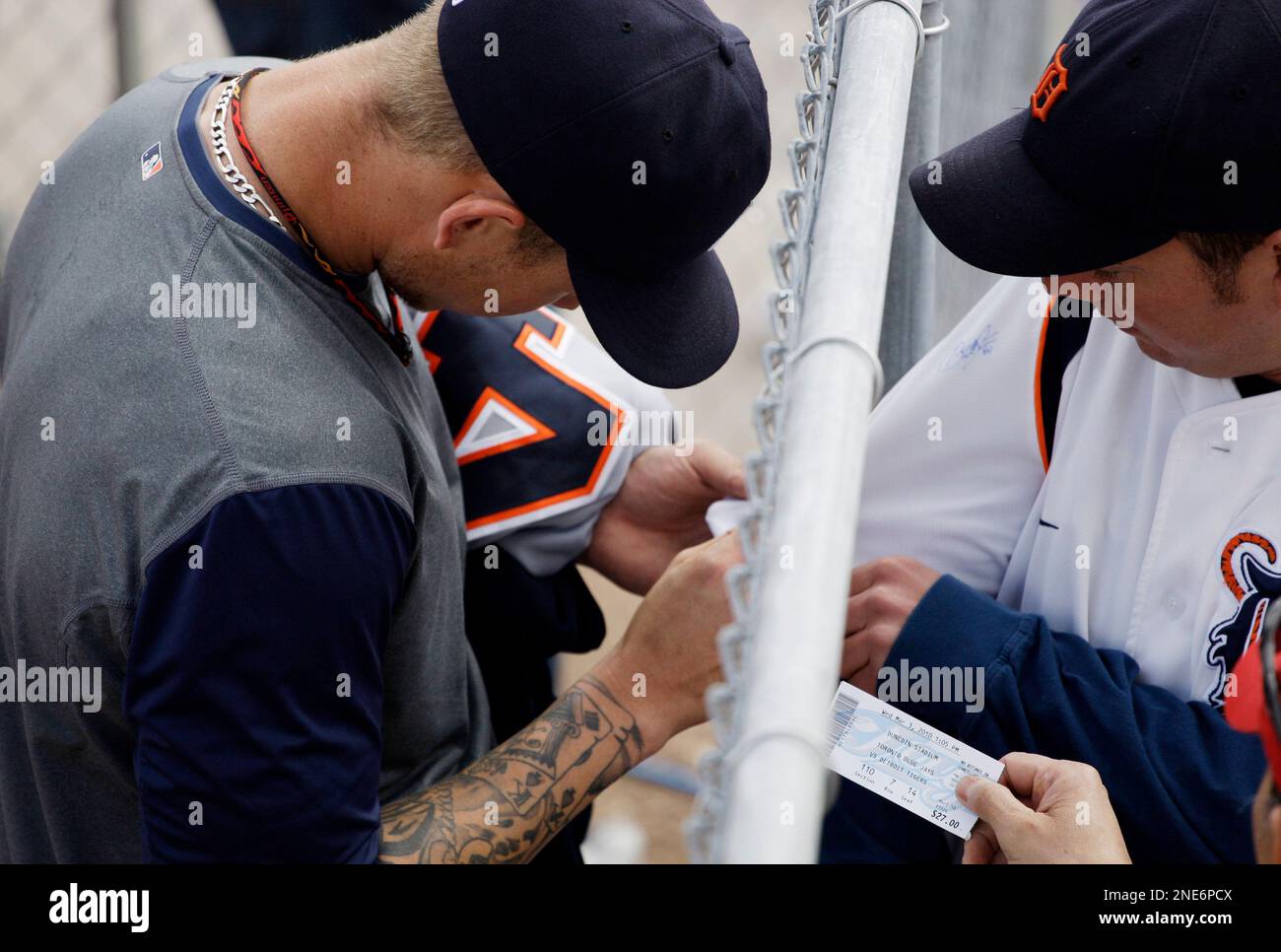 Detroit Tigers' Ryan Perry, left, signs autographs through a fence ...