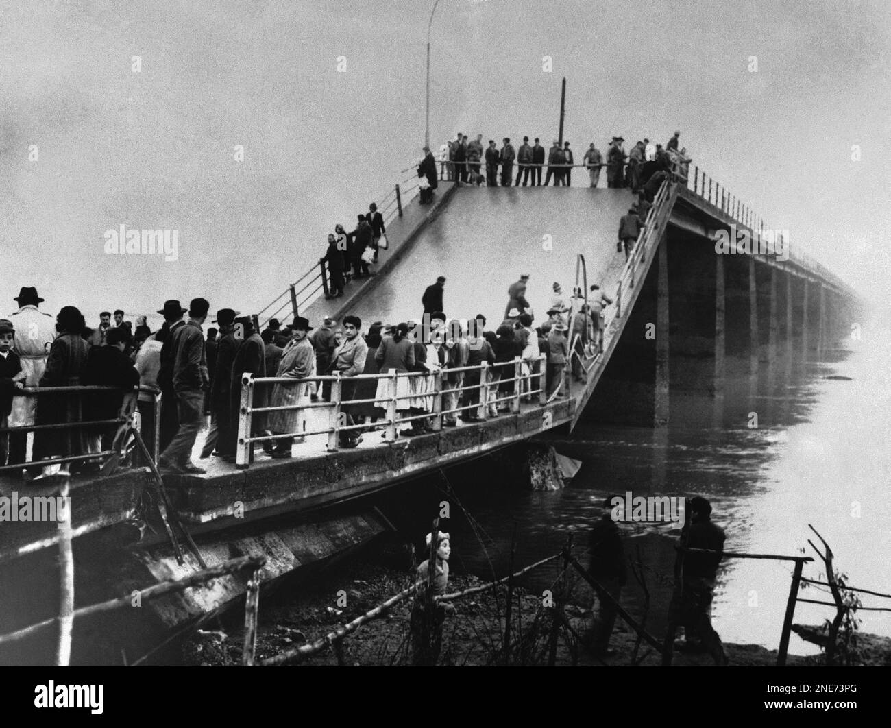 Survivors stand on part of a collapsed bridge over the Bio Rio River ...