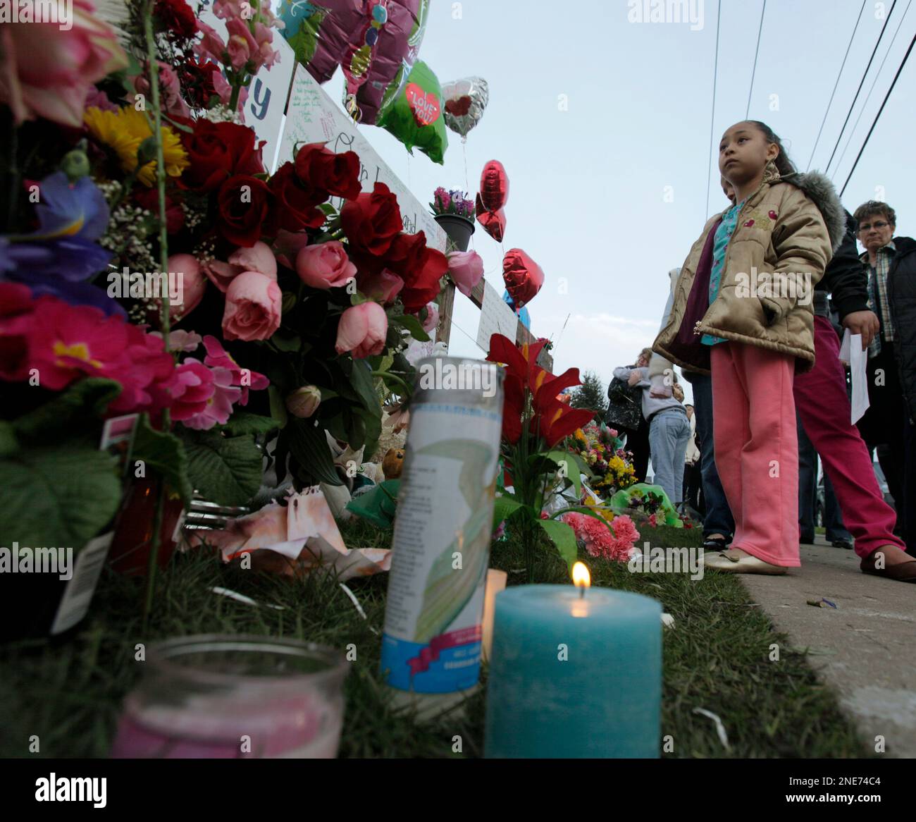An unidentified girl looks at candles and flowers at a memorial to ...