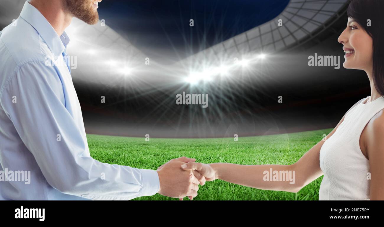 Composition of businessman and businesswoman shaking hands over sports ...