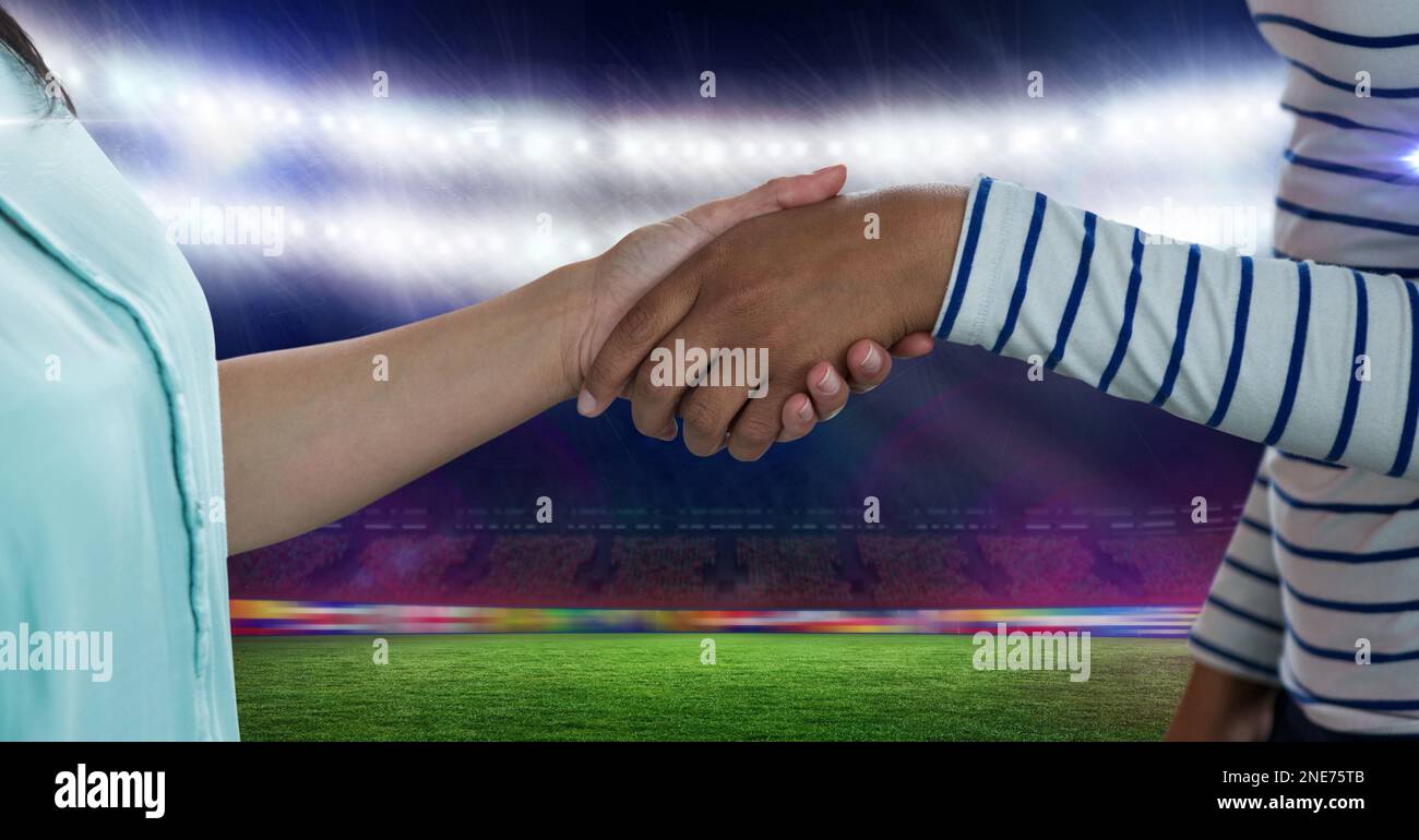 Composition of two businesswomen shaking hands over sports stadium ...