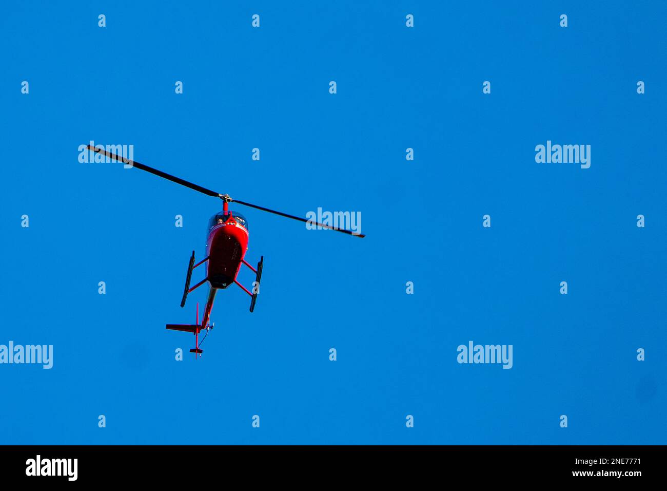 Red helicopter in flight on a blue sky, sunny day. Rotary. wing ...