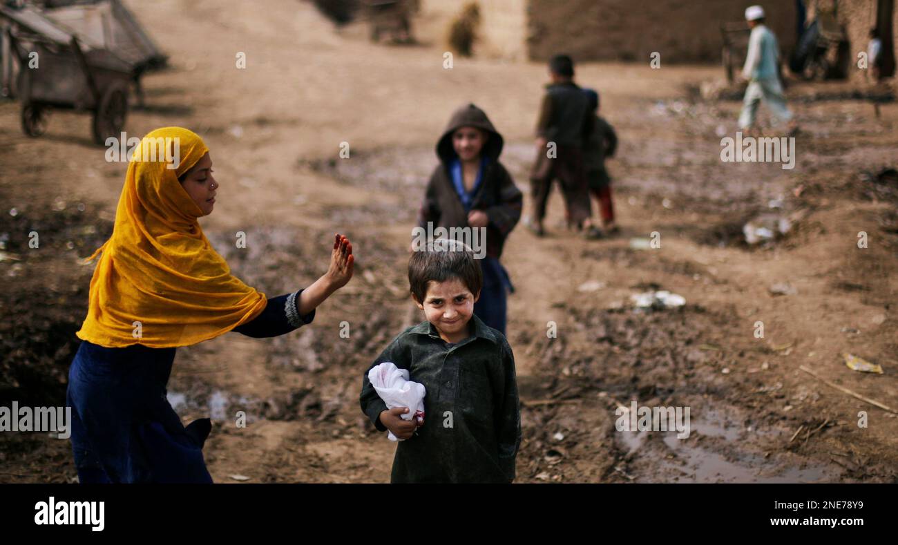An Afghan refugee boy, center, looks on, as a girl, left, approaches to ...